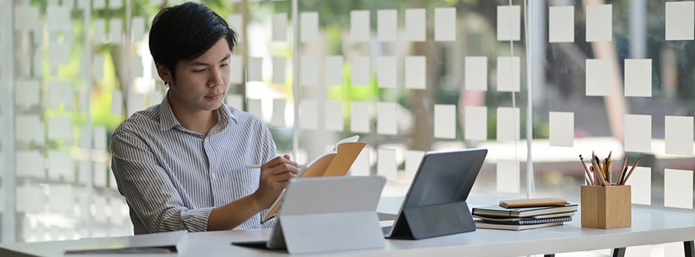 Student with a laptop and stationary preparing to complete thesis to ...